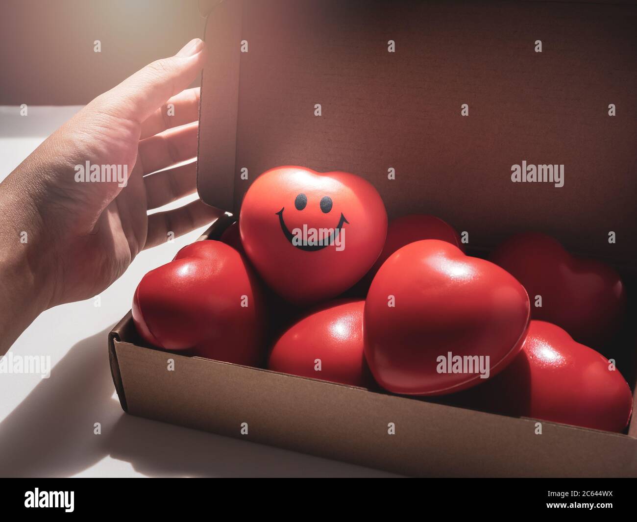 Hand opening brown paper craft box with red hearts with happy and ...
