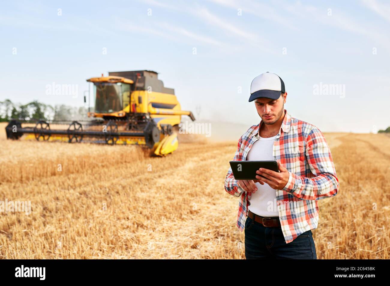 Precision farming. Farmer holding tablet for combine harvester guidance ...