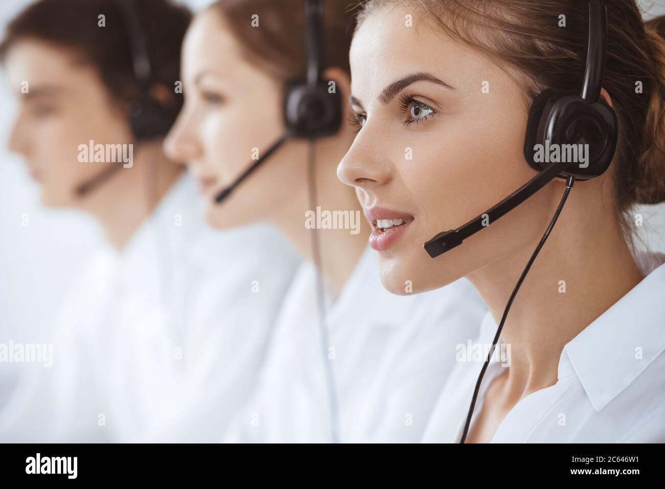 Call center. Beautiful young woman using headset and computer to help ...