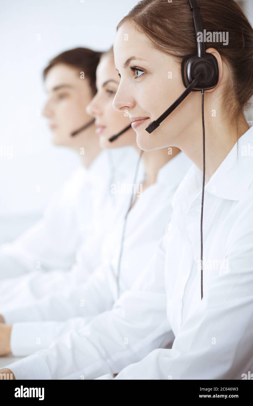 Call center. Beautiful young woman using headset and computer to help ...