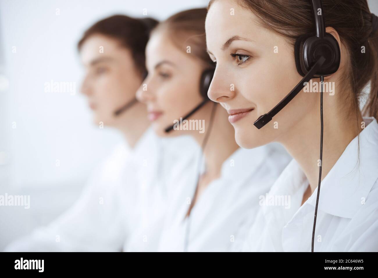 Call center. Beautiful young woman using headset and computer to help ...