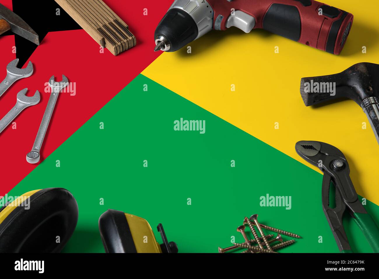 Guinea flag on repair tool concept wooden table background. Mechanical ...