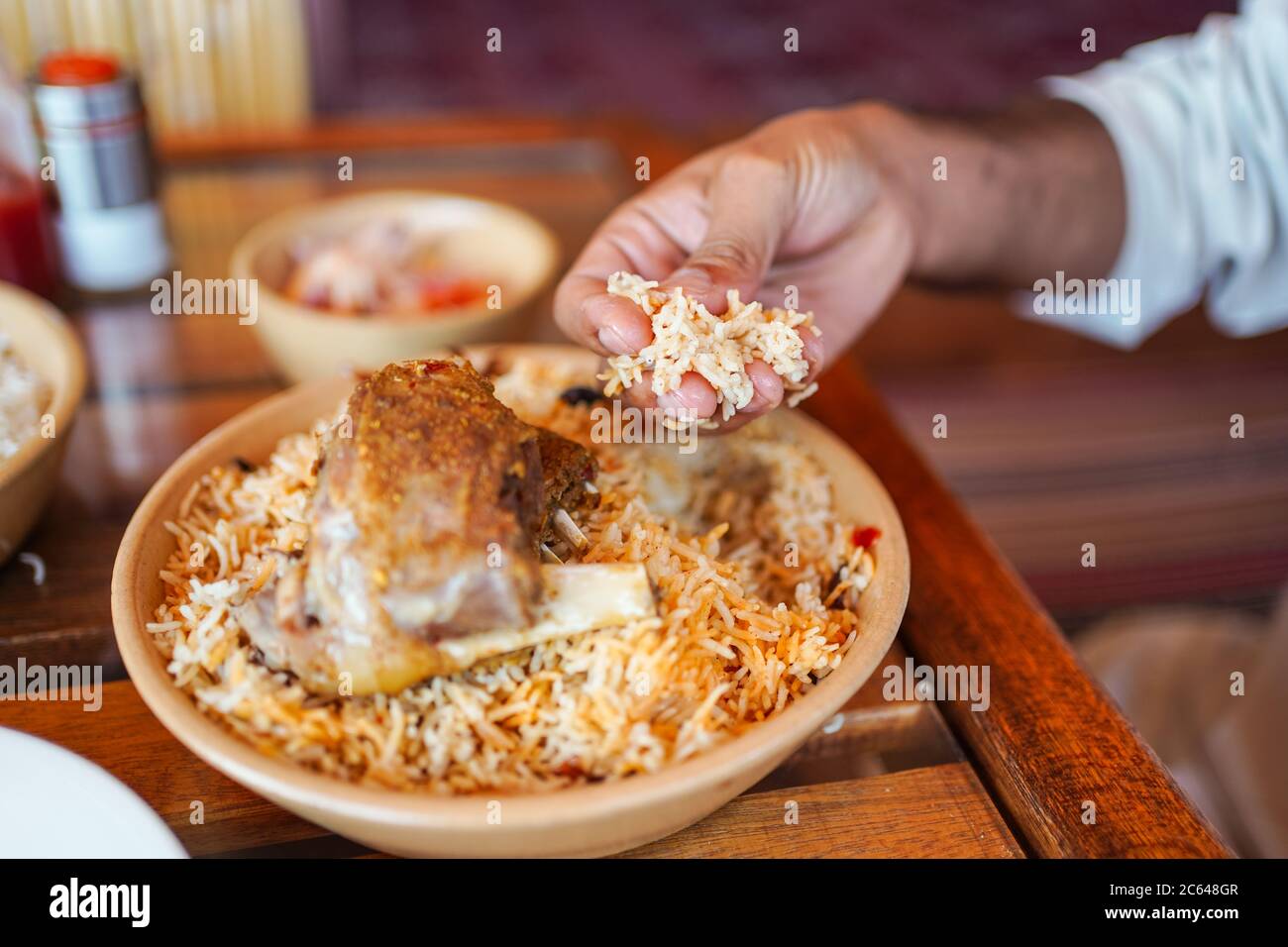 Man eating using hand a traditional biryani rice and chicken dish in ...