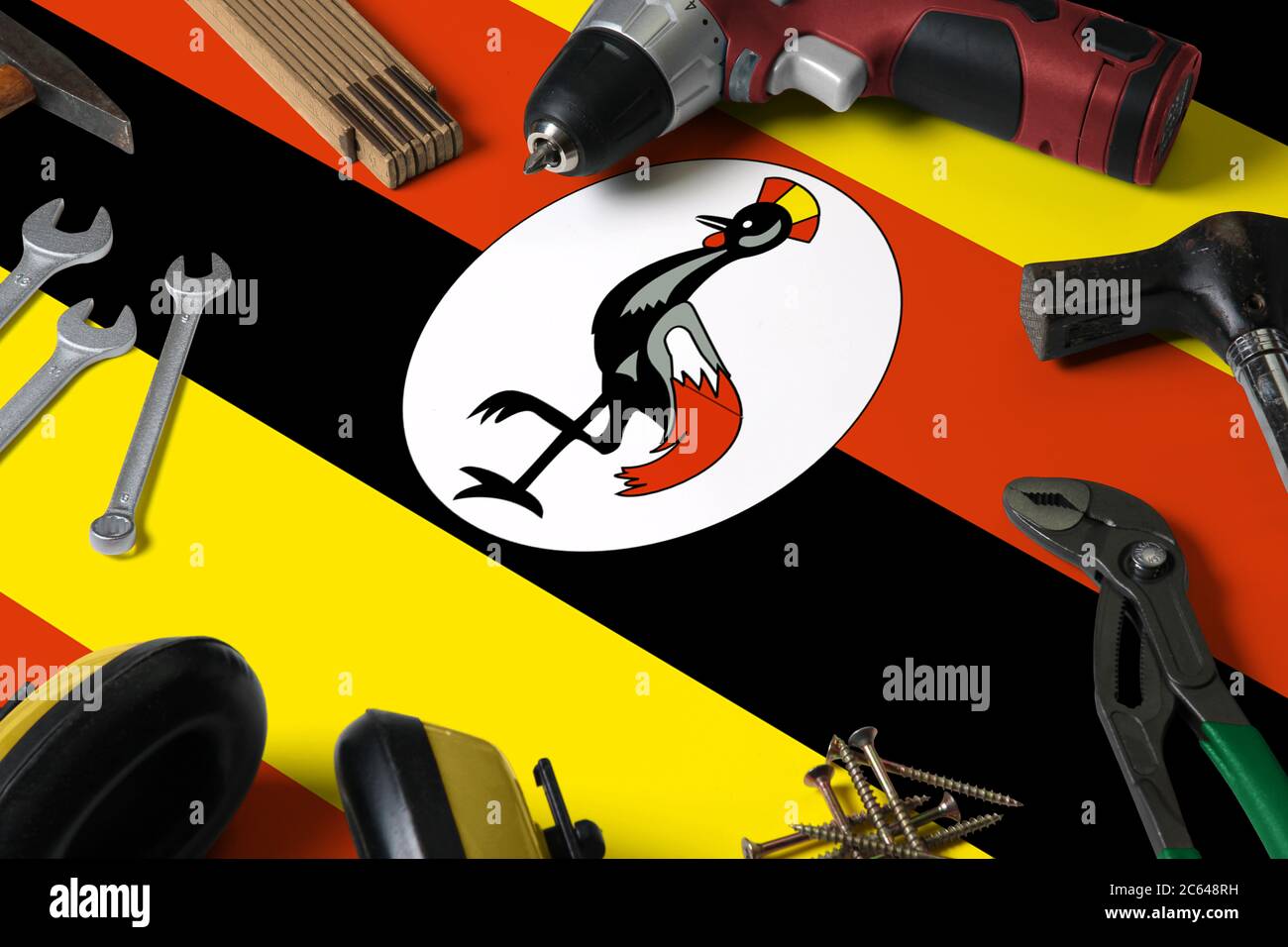 Uganda flag on repair tool concept wooden table background. Mechanical ...