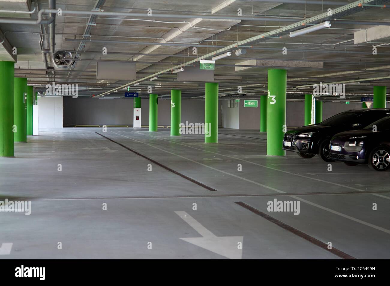 Underground empty parking garage with overhead lights and an exit sign ...