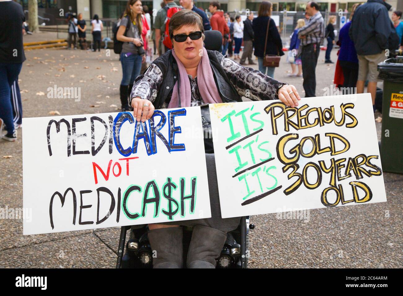 A protester in a wheelchair holds signs at the Save Medicare rally ...