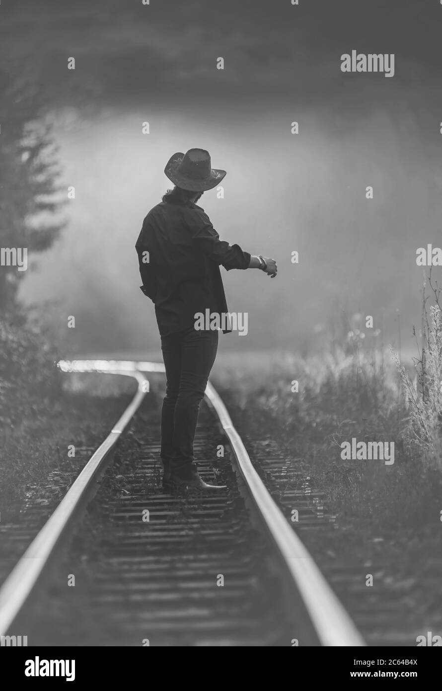 Cowboy walking on a railway line Stock Photo - Alamy