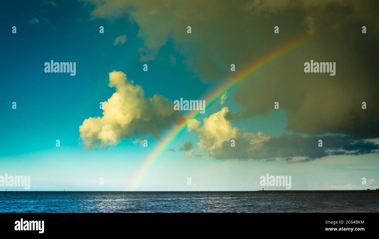 landscape view on cloudy sky with colorful rainbow at sea or ocean ...