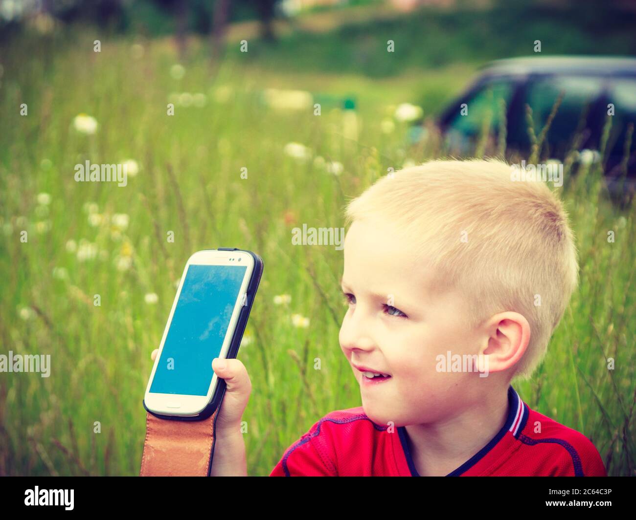 Little boy child kid playing games on smartphone mobile phone outdoor ...