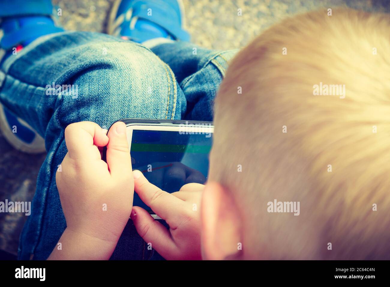 Little boy child kid playing games on smartphone mobile phone outdoor ...