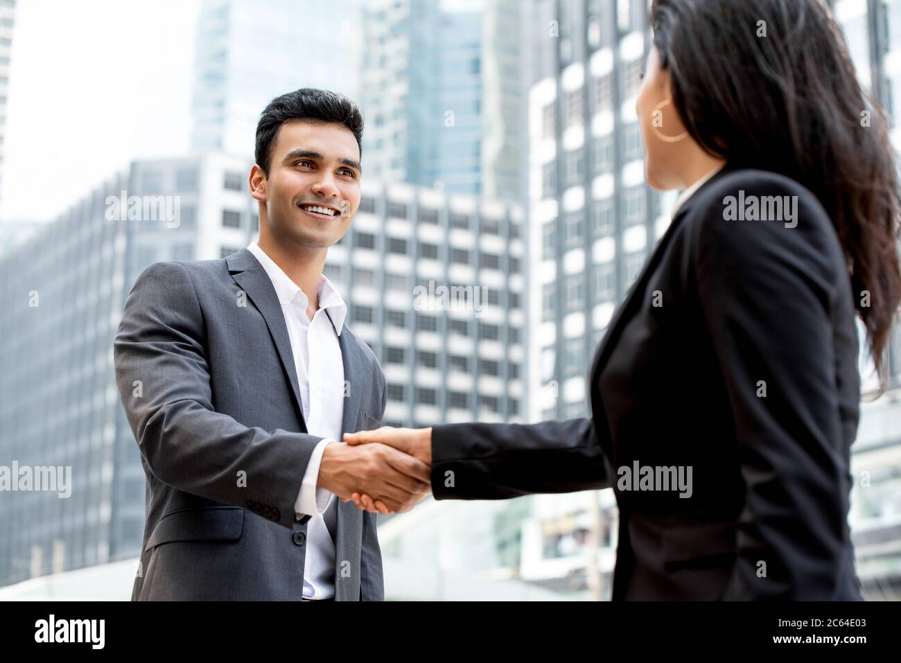 Smiling handsome young Indian businessman making handshake with ...