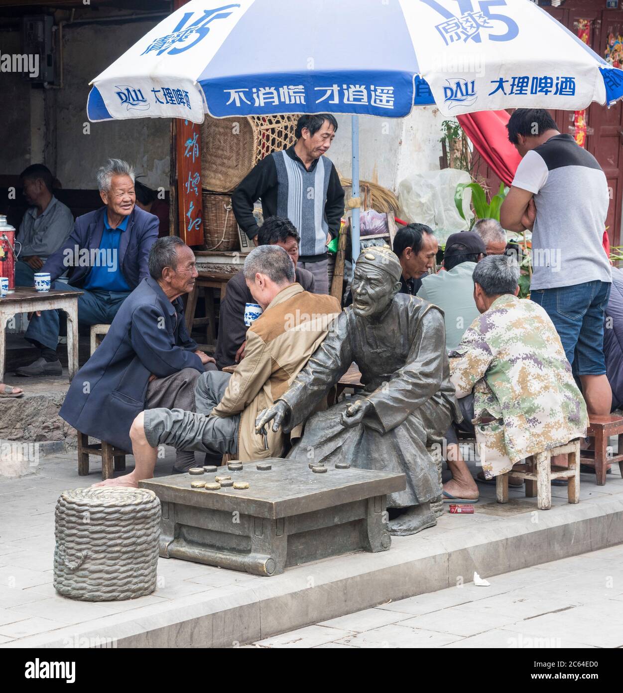 A group of Chinese men playing a traditional mahjong game outdoors in ...