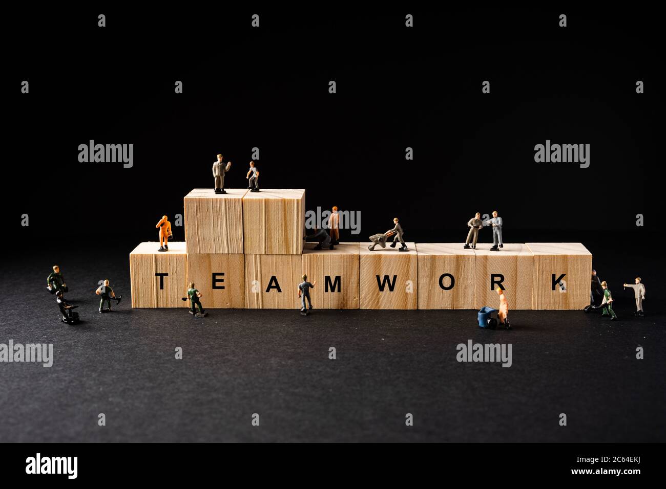 Teamwork concept. Miniature builders figure with wooden blocks with ...