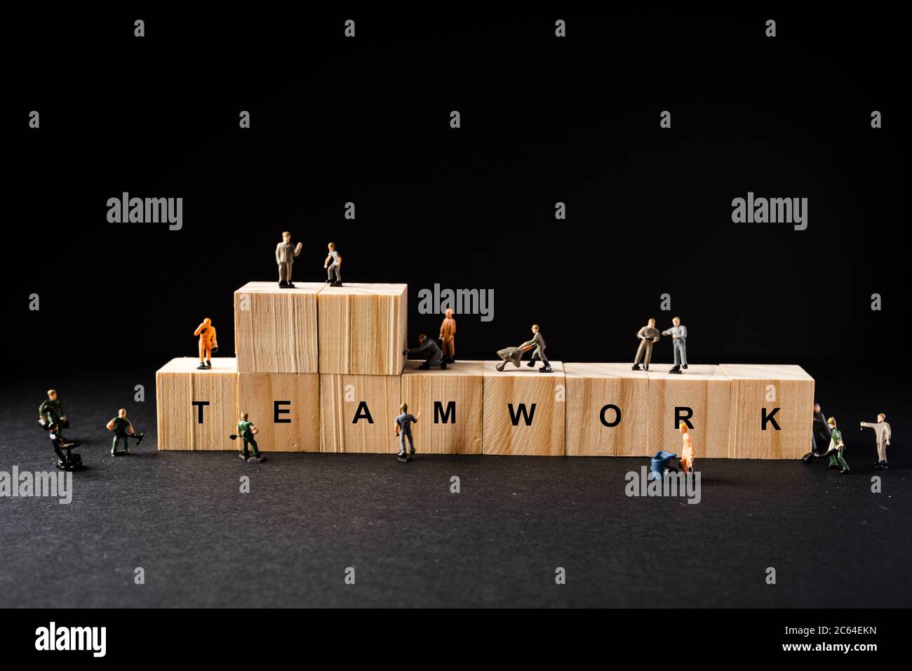 Teamwork concept. Miniature builders figure with wooden blocks with ...