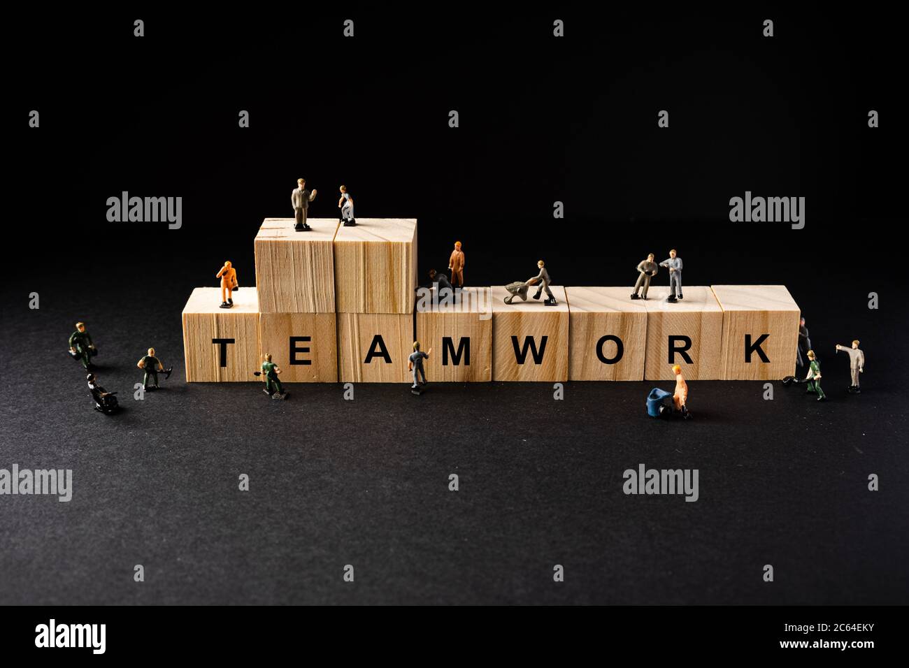 Teamwork concept. Miniature builders figure with wooden blocks with ...