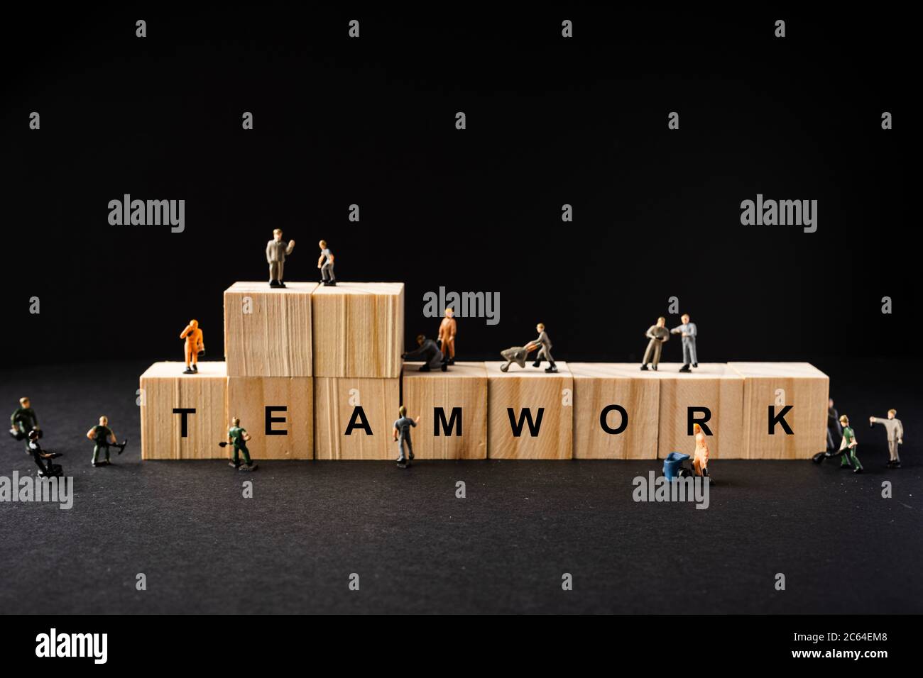 Teamwork concept. Miniature builders figure with wooden blocks with ...