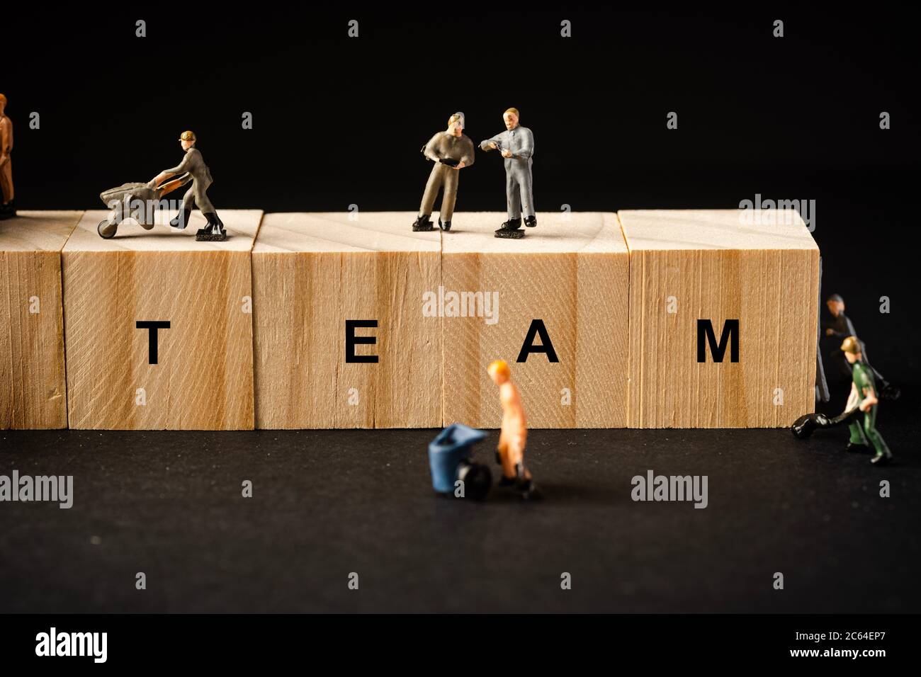 Teamwork concept. Miniature builders figure with wooden blocks with ...