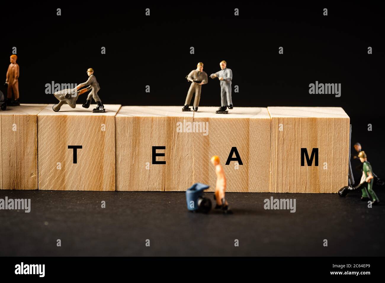 Teamwork concept. Miniature builders figure with wooden blocks with ...