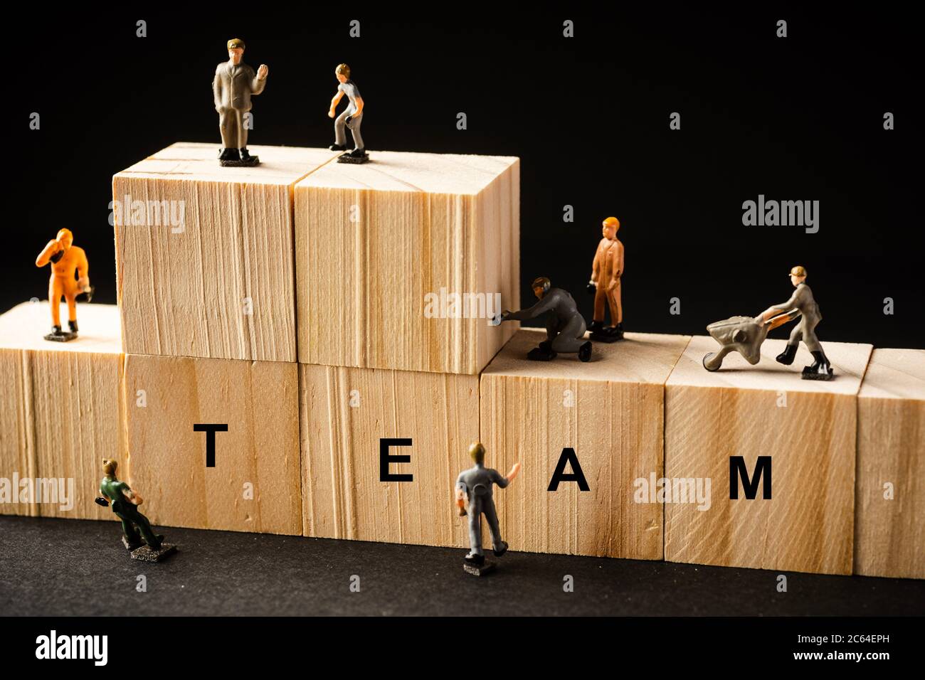 Teamwork concept. Miniature builders figure with wooden blocks with ...