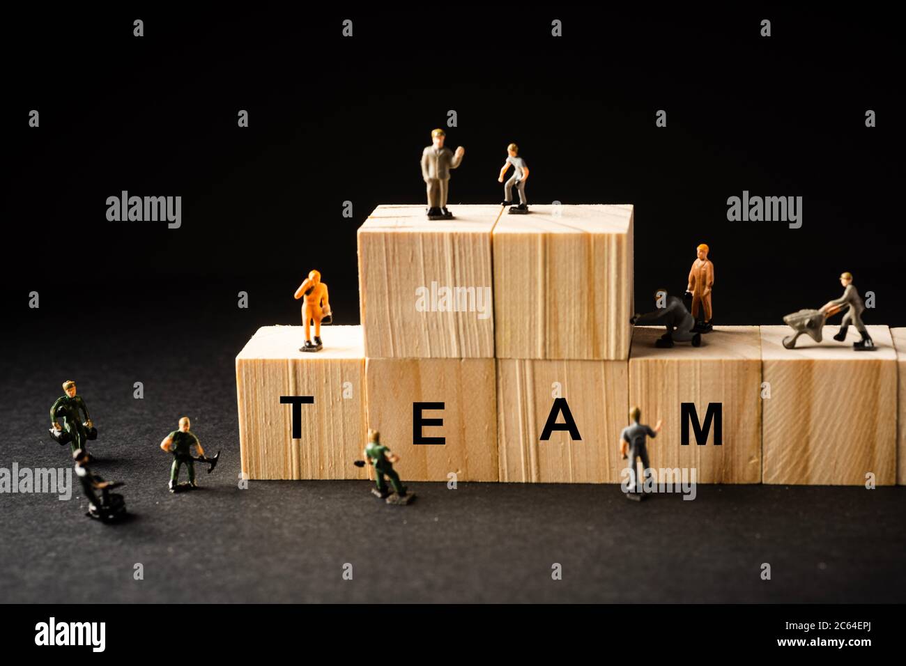 Teamwork concept. Miniature builders figure with wooden blocks with ...