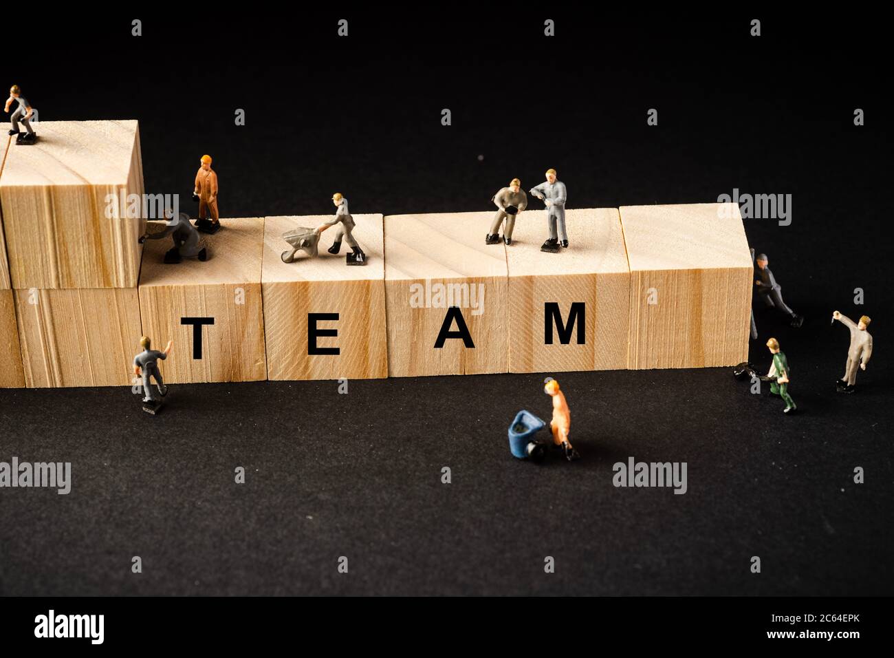 Teamwork concept. Miniature builders figure with wooden blocks with ...