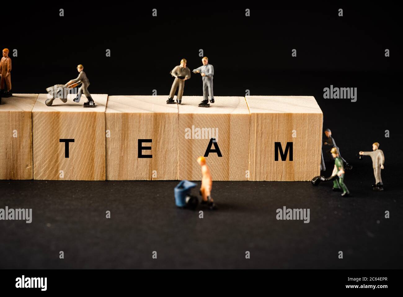Teamwork concept. Miniature builders figure with wooden blocks with ...