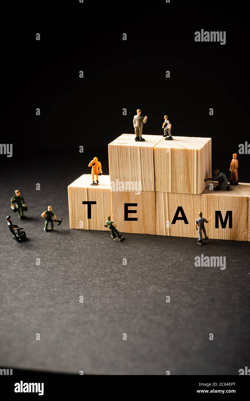 Teamwork concept. Miniature builders figure with wooden blocks with ...