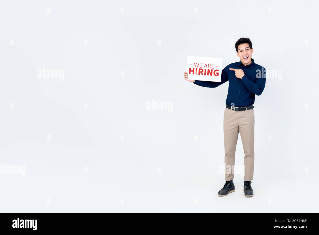 Portrait of smiling handsome Asian businessman holding and pointing to ...