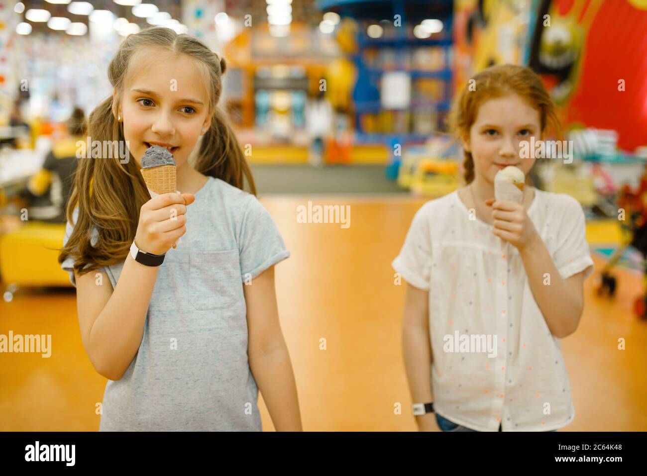 Two girls eats ice cream in entertainment center Stock Photo - Alamy