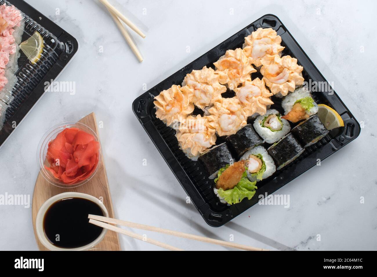 Sushi rolls set served on dark wooden board and plastic boxes ...