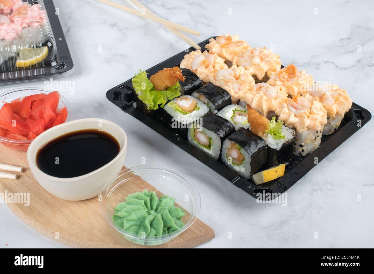 Sushi rolls set served on dark wooden board and plastic boxes ...