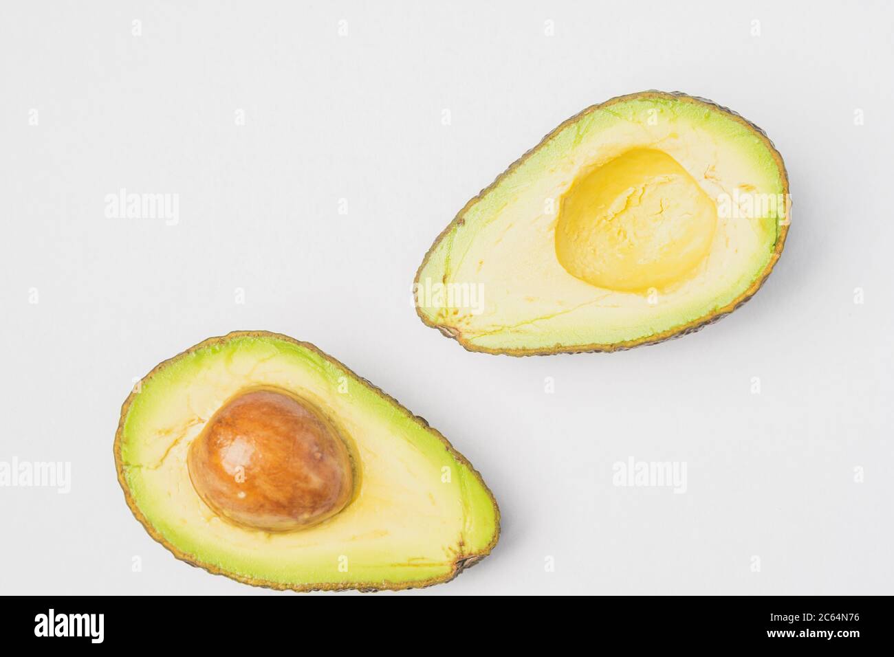 An avocado cut into half on white background Stock Photo - Alamy