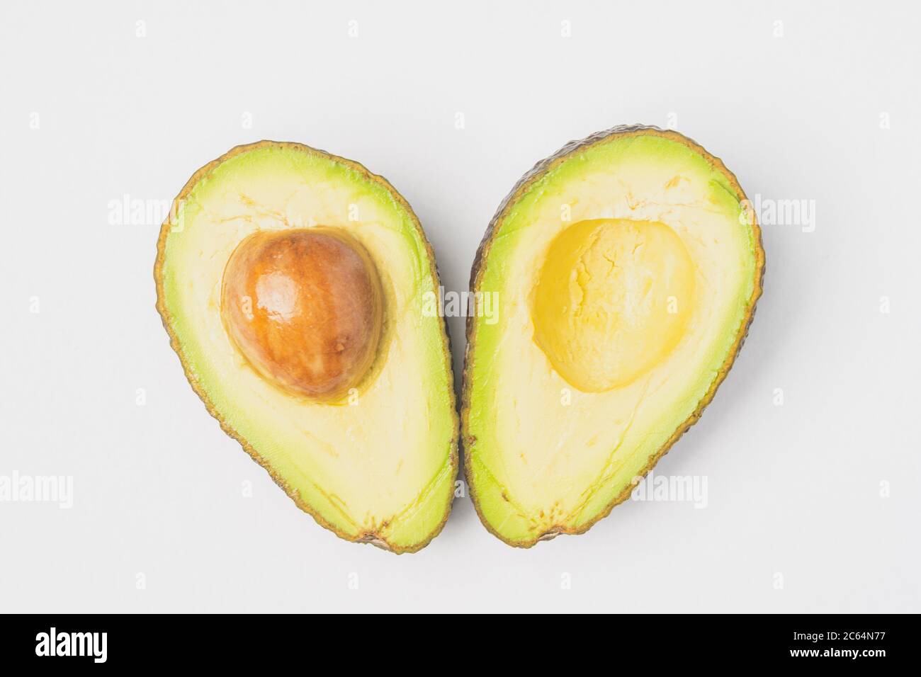 An avocado cut into half on white background Stock Photo - Alamy