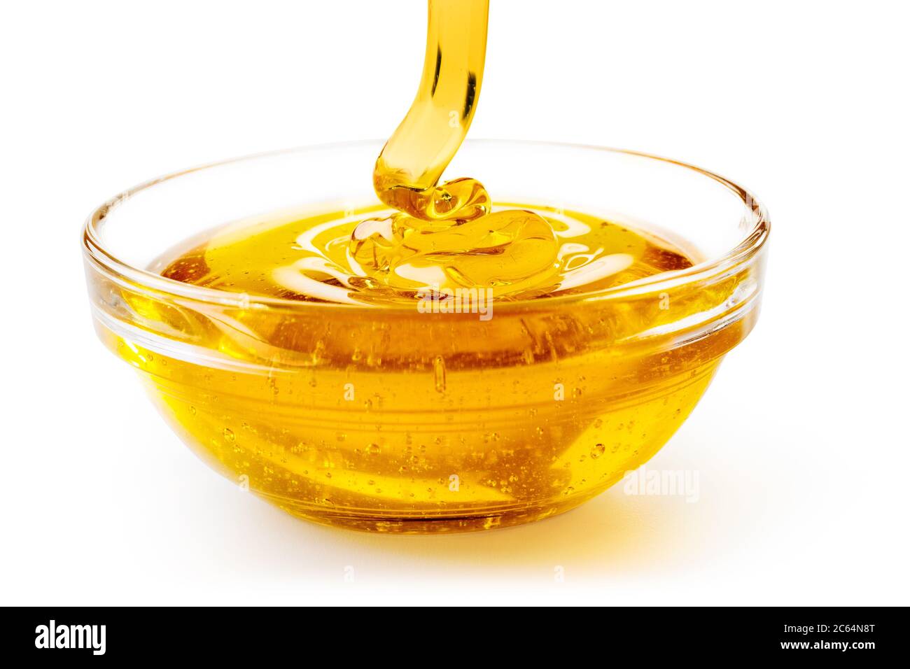 close up of honey dropping into a glass bowl isolated on white ...