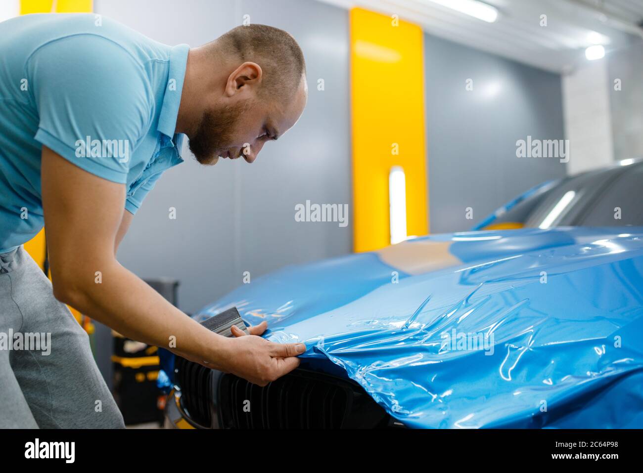Car wrapper puts protective foil or film on hood Stock Photo - Alamy