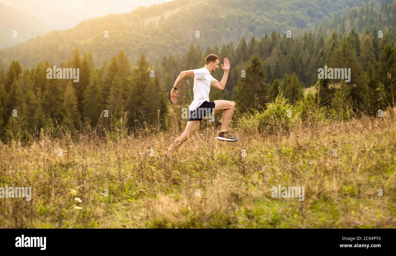 Running fitness man sprinting outdoors with beautiful mountains ...