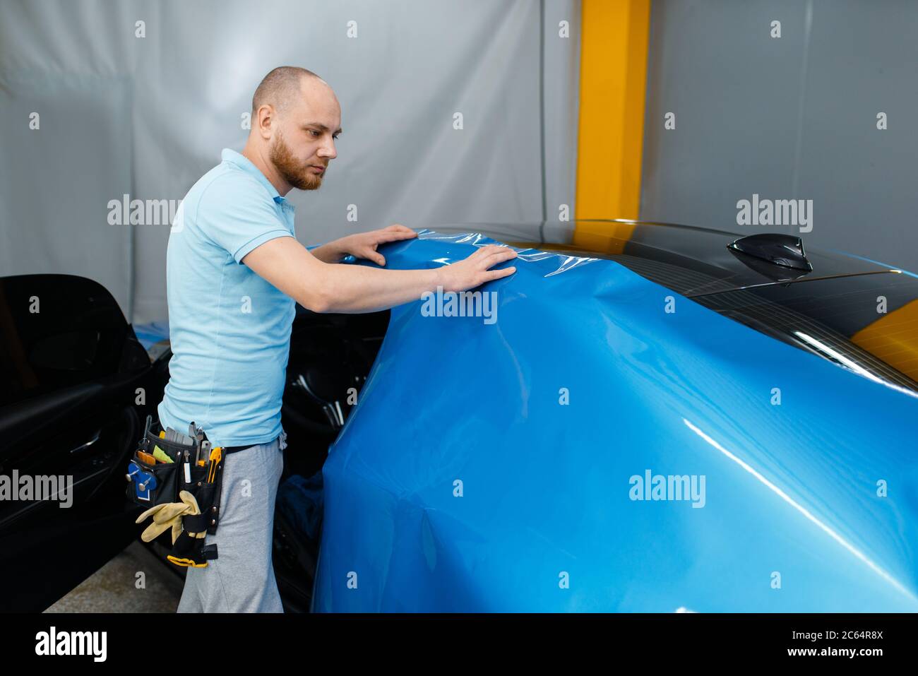 Car wrapping, man with tool belt puts vinyl film Stock Photo - Alamy