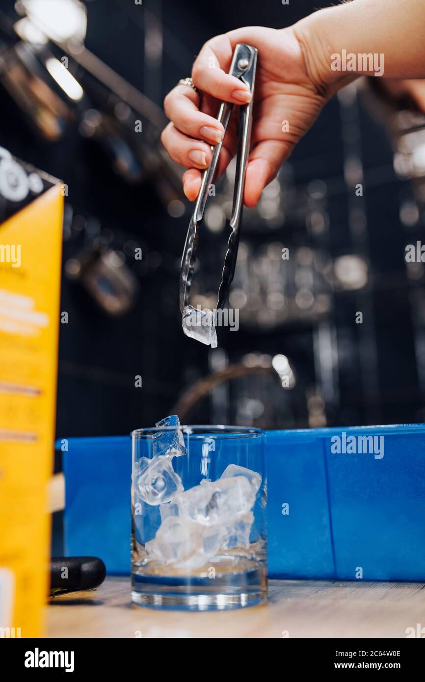 Crushed ice with bar forceps in a glass for a cocktail - the work of ...