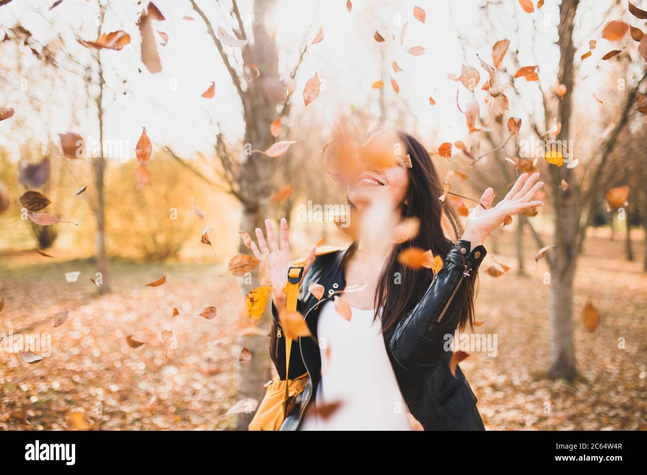 Cheerful happy girl waving her hands from falling autumn leaves - a ...