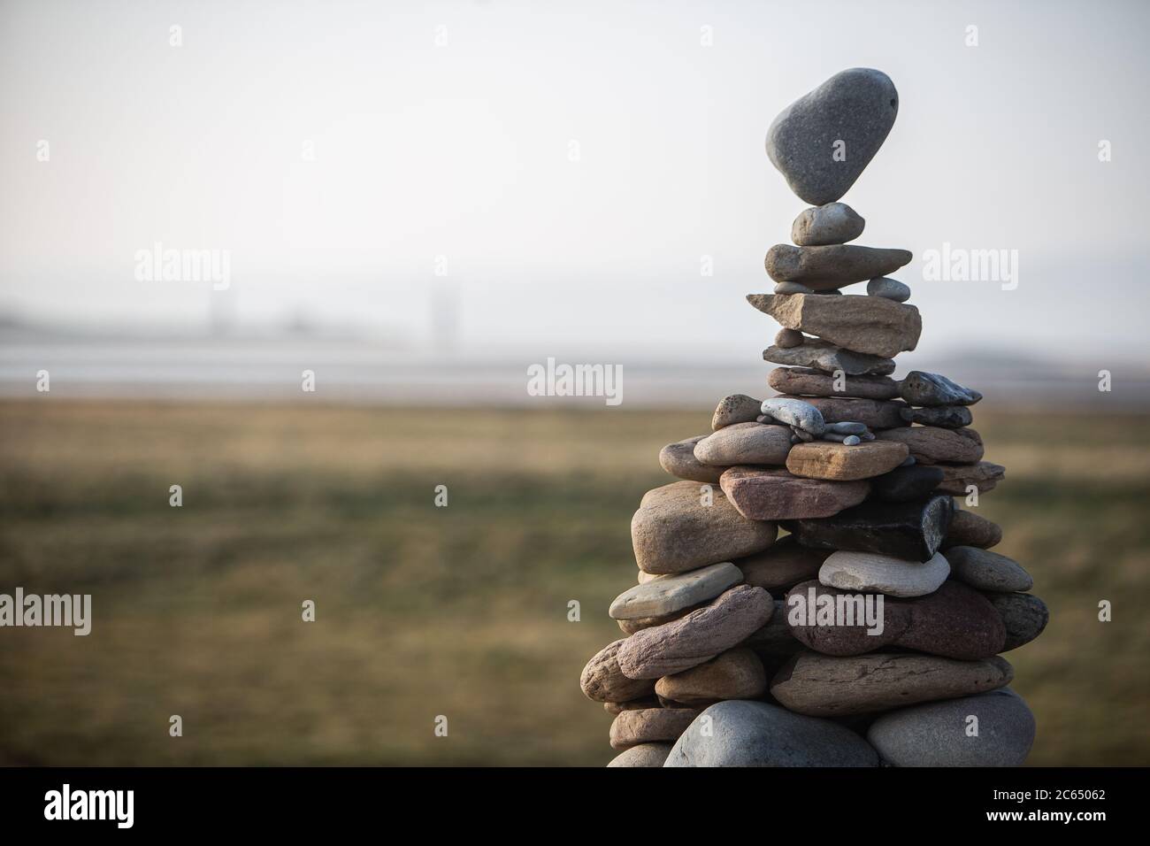 A tower of stones of various sizes stacked in a cairn, the top stone ...