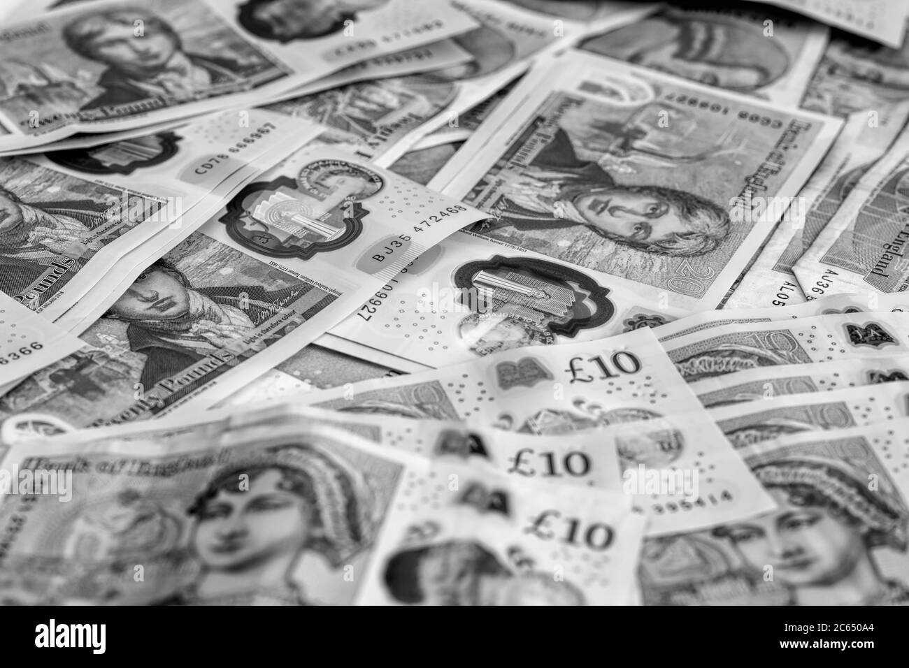 Scattering of ten pound and twenty pound notes face down in black and ...