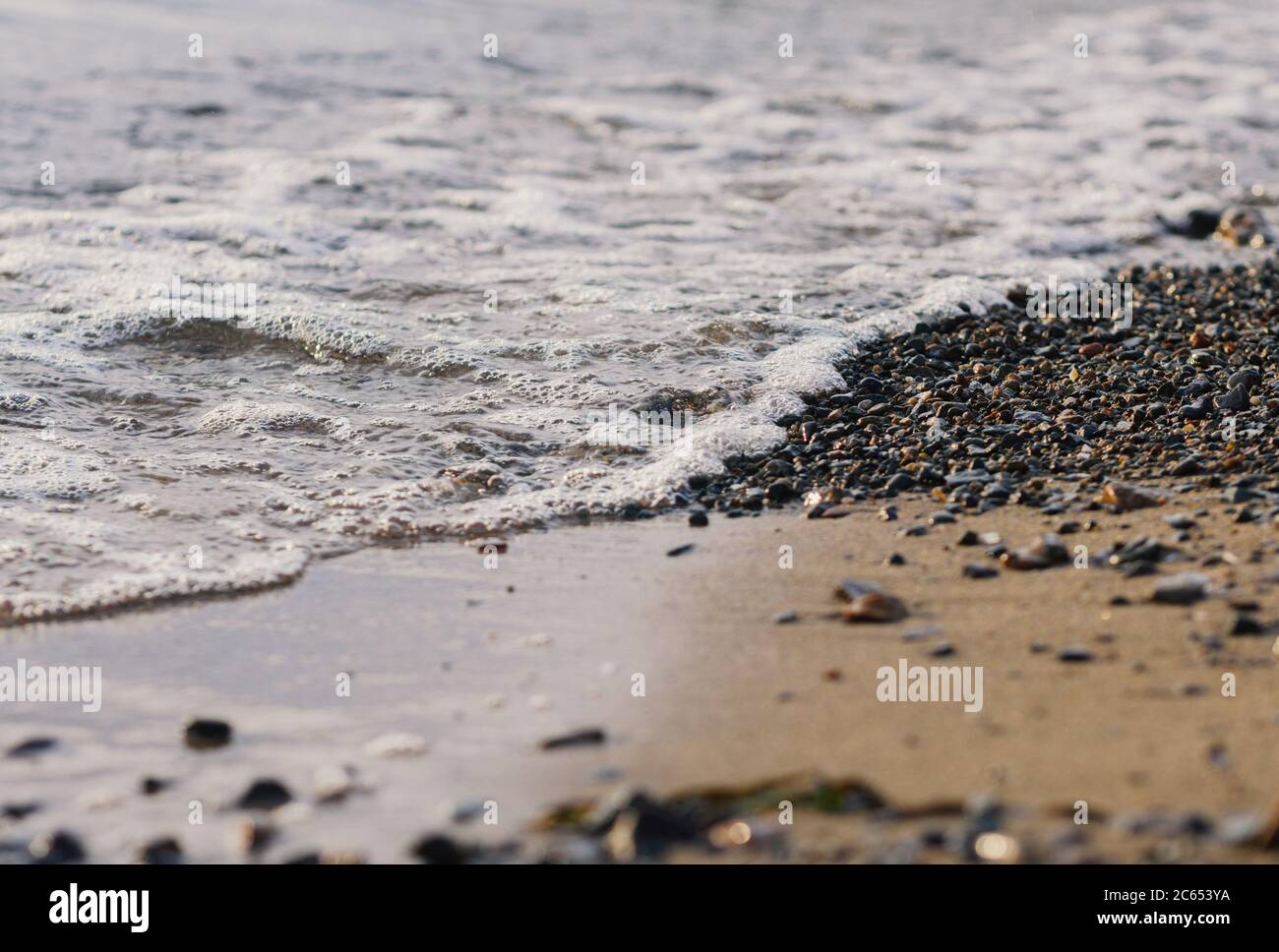 Waves at the seashore at sunset. Selective focus with shallow depth of ...