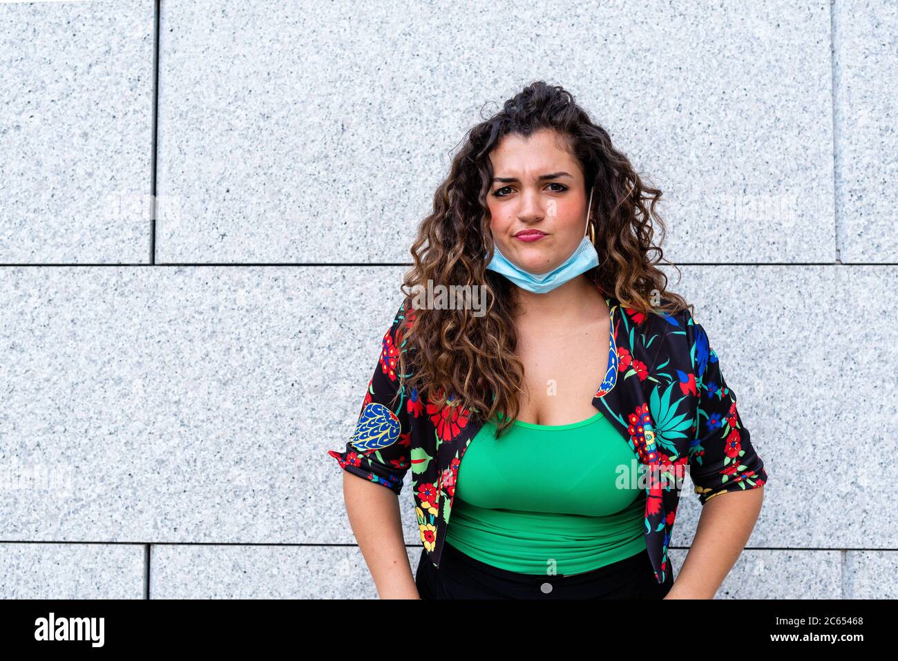 dubious and comic expression of a young brown and curly woman, wearing ...