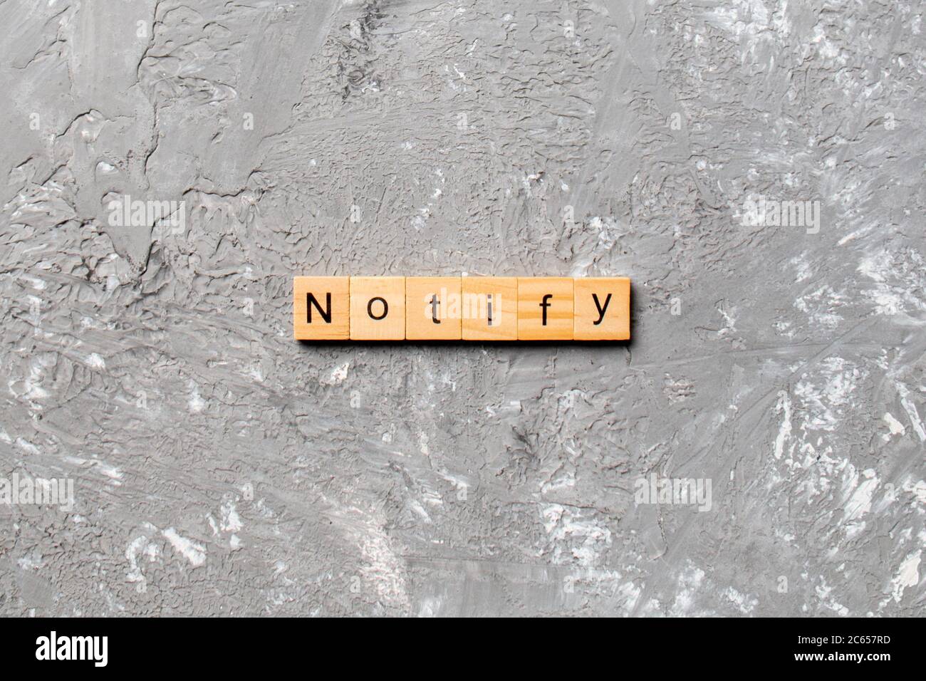 NOTIFY word written on wood block. NOTIFY text on cement table for your ...