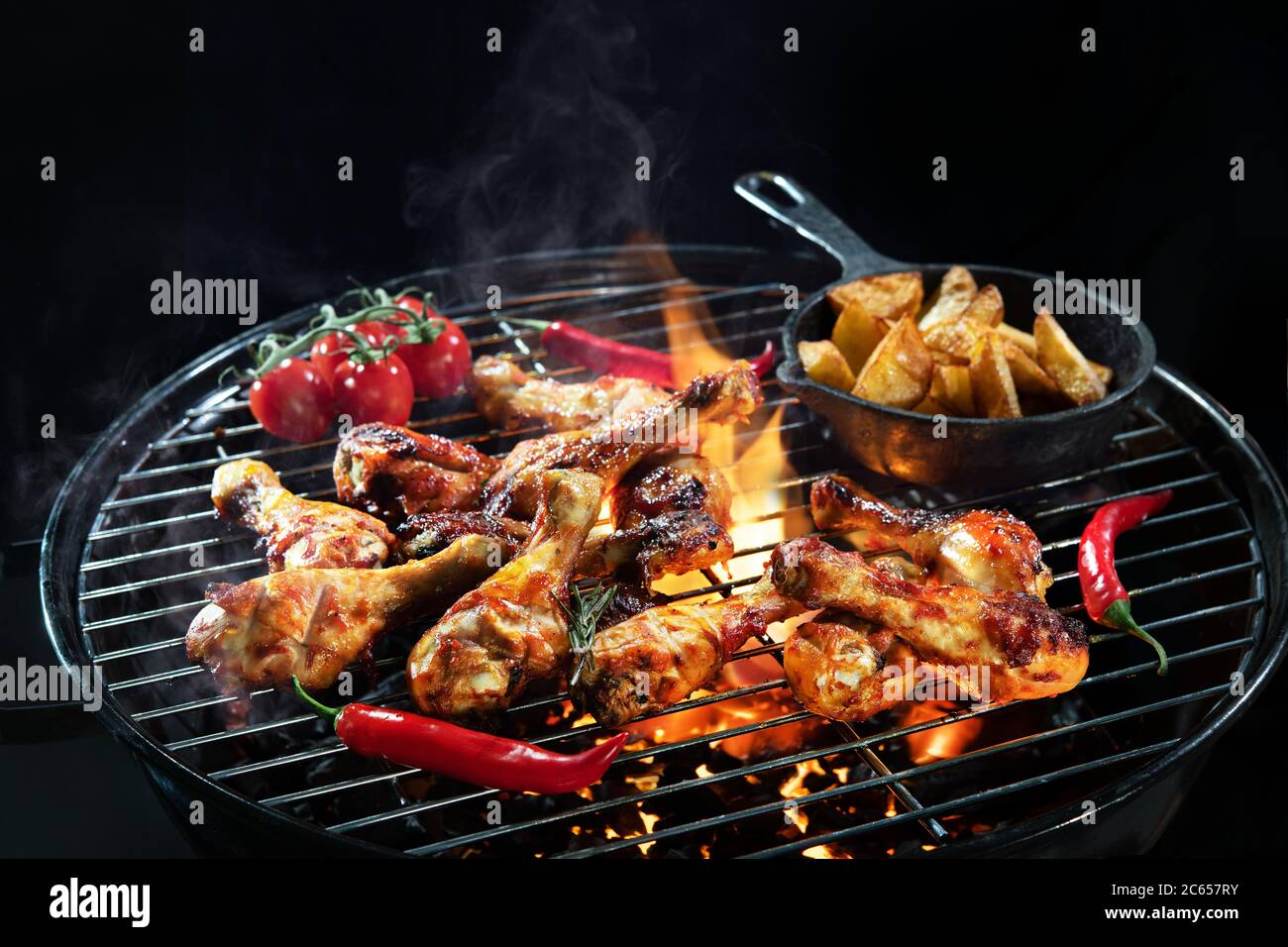 Grilled chicken legs or drumsticks on the hot flaming barbecue grill ...