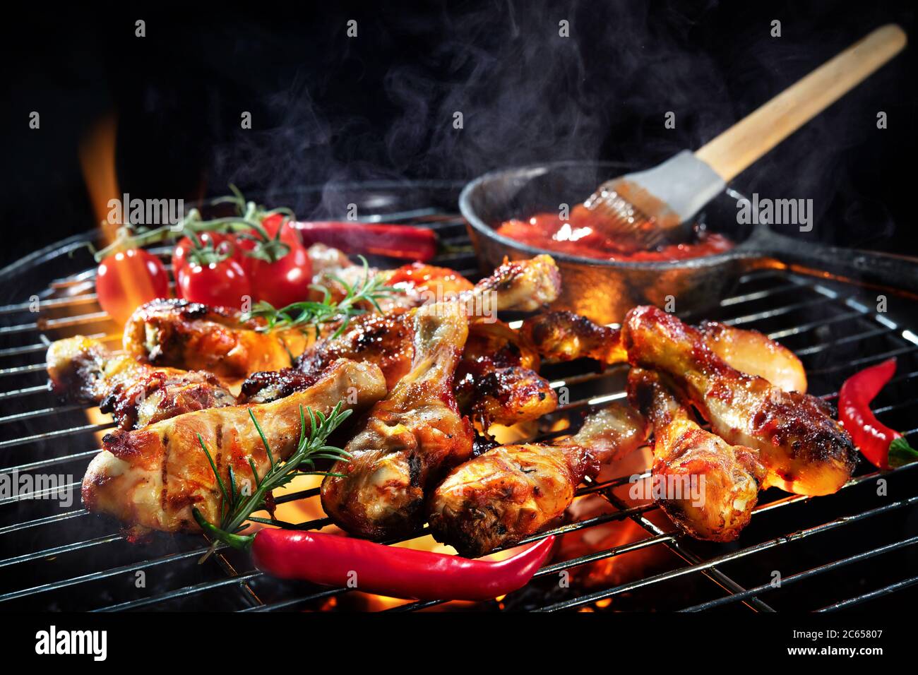 Grilled chicken legs or drumsticks on the hot flaming barbecue grill ...