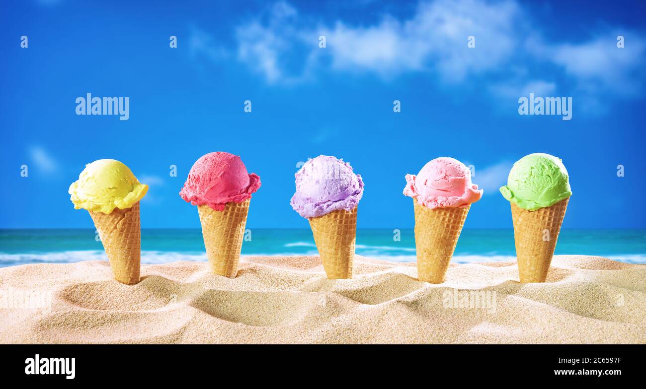 Ice creams cones and seashells in the sand on the beach with ocean ...