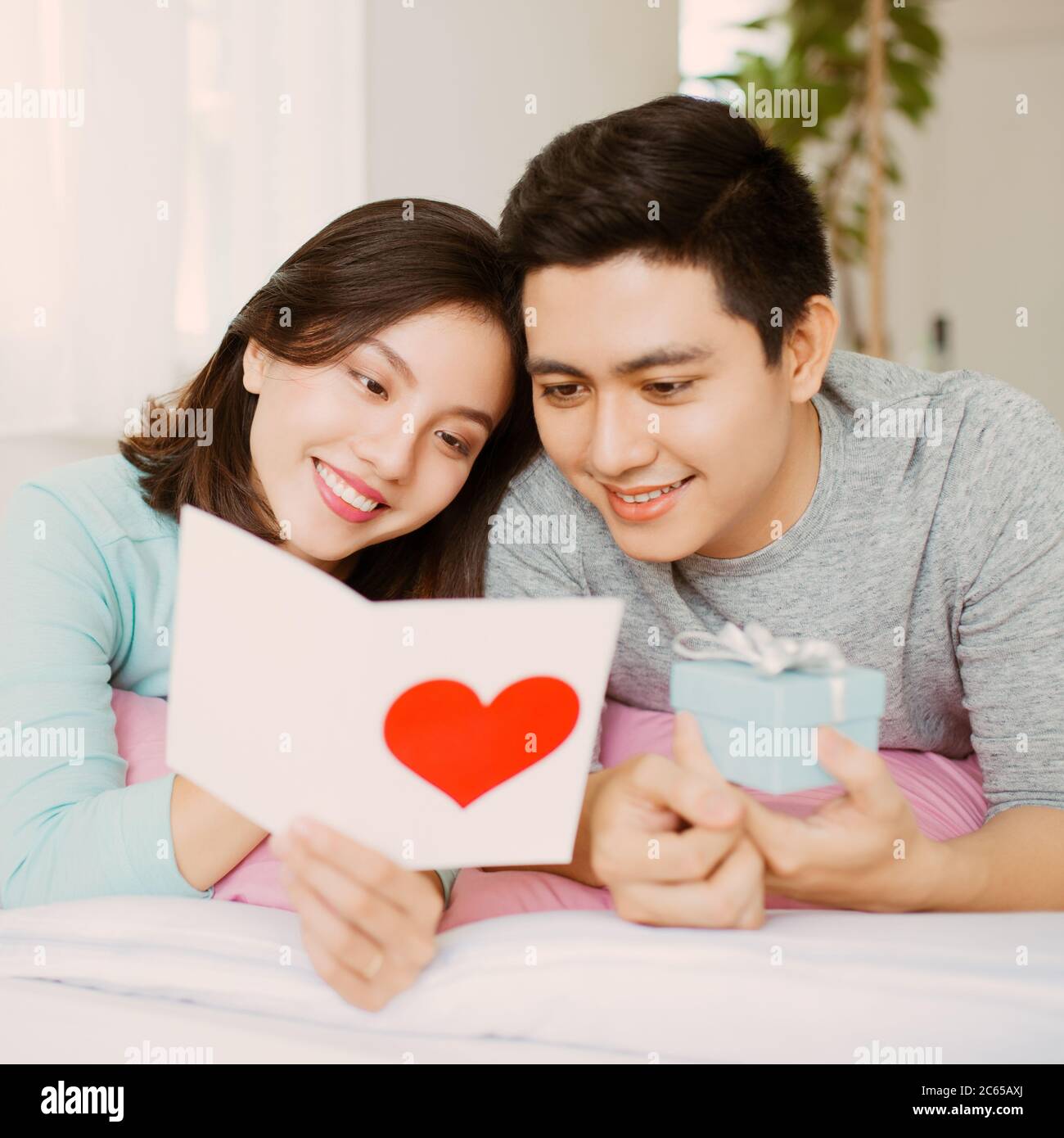 Couple reading envelope together and lying on bed Stock Photo - Alamy