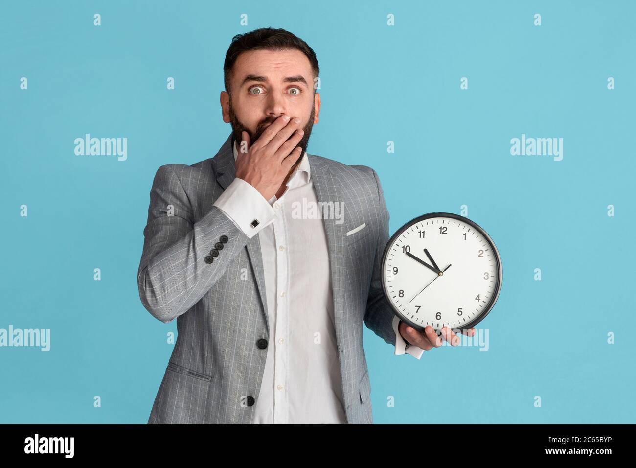 Missed deadline. Shocked corporate employee with clock on blue ...