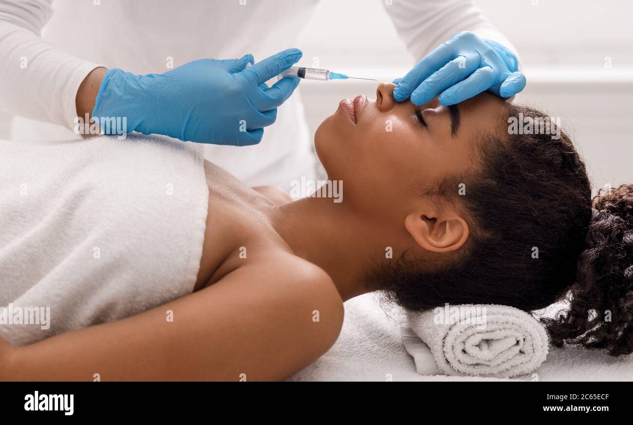 Black lady receiving beauty injections for nose zone Stock Photo - Alamy